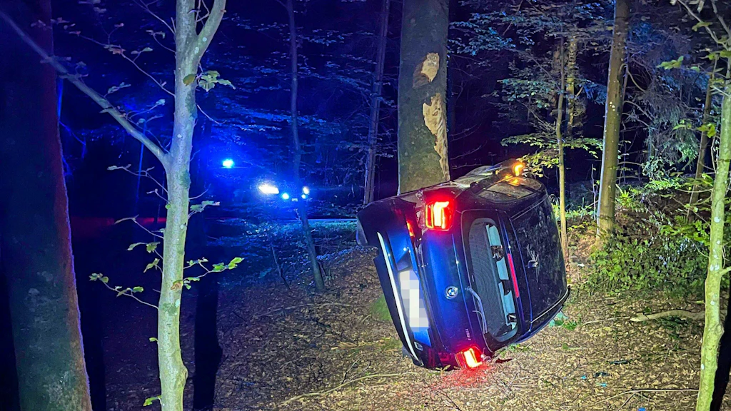 BMW crashes into a tree and comes to rest on its side